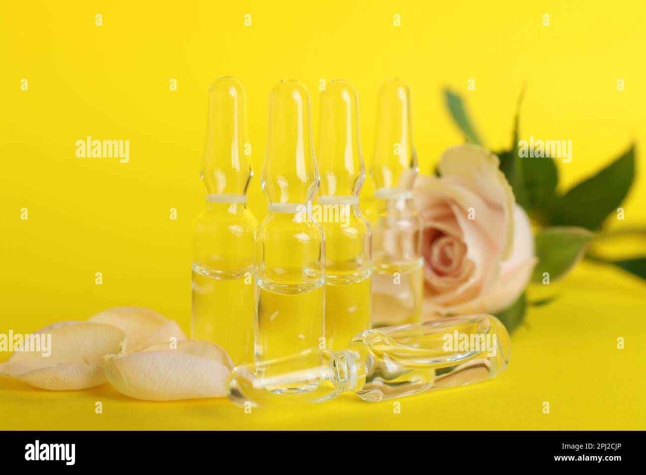 Pharmaceutical ampoules with medication and flower on yellow background ...