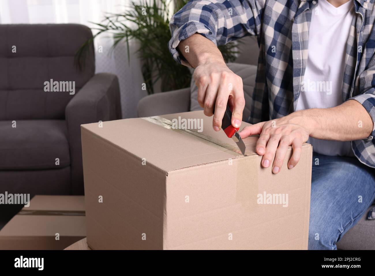 Man using utility knife to open parcel at home, closeup Stock Photo - Alamy