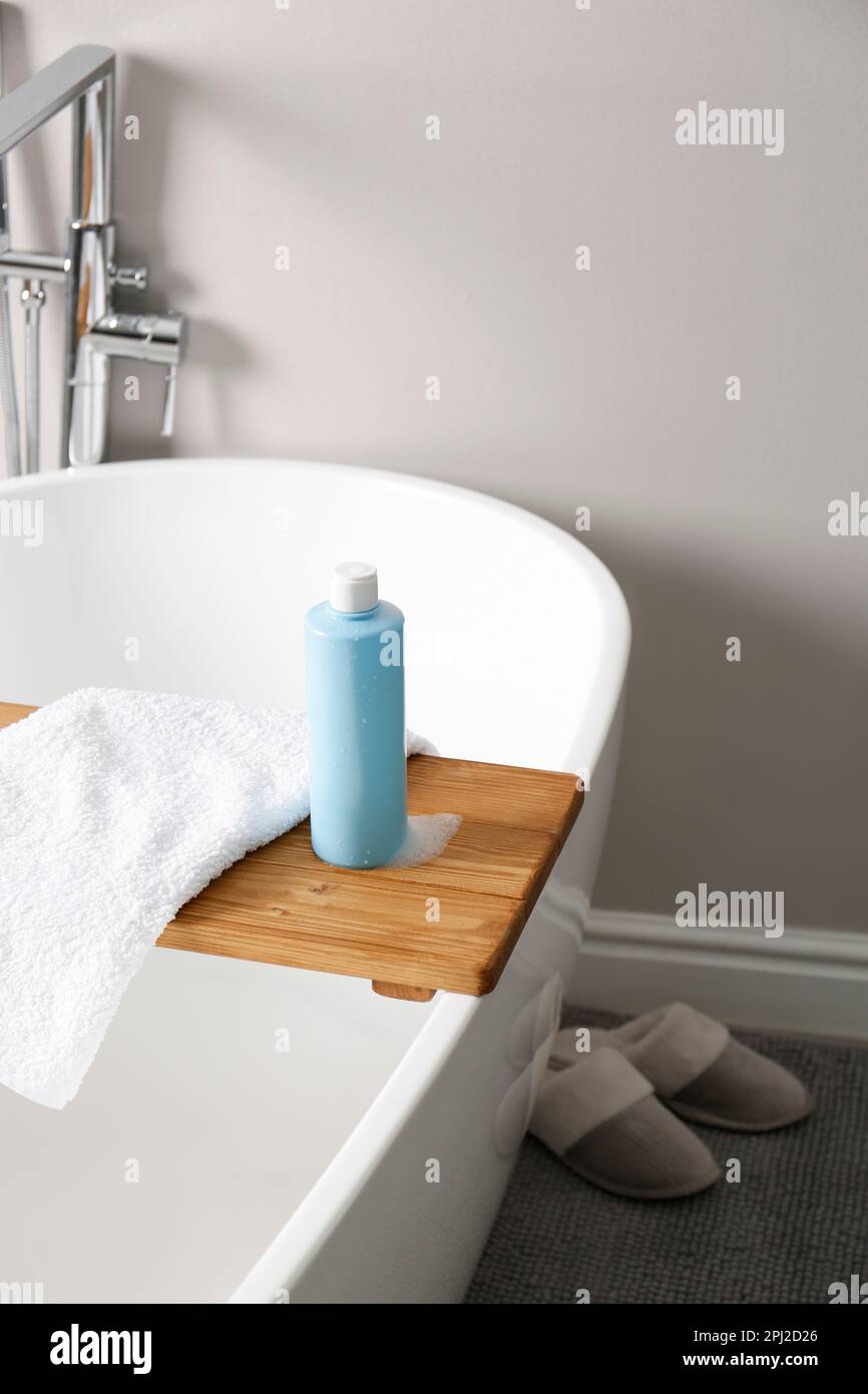 Bottle of bubble bath with foam and towel on tub in bathroom Stock ...