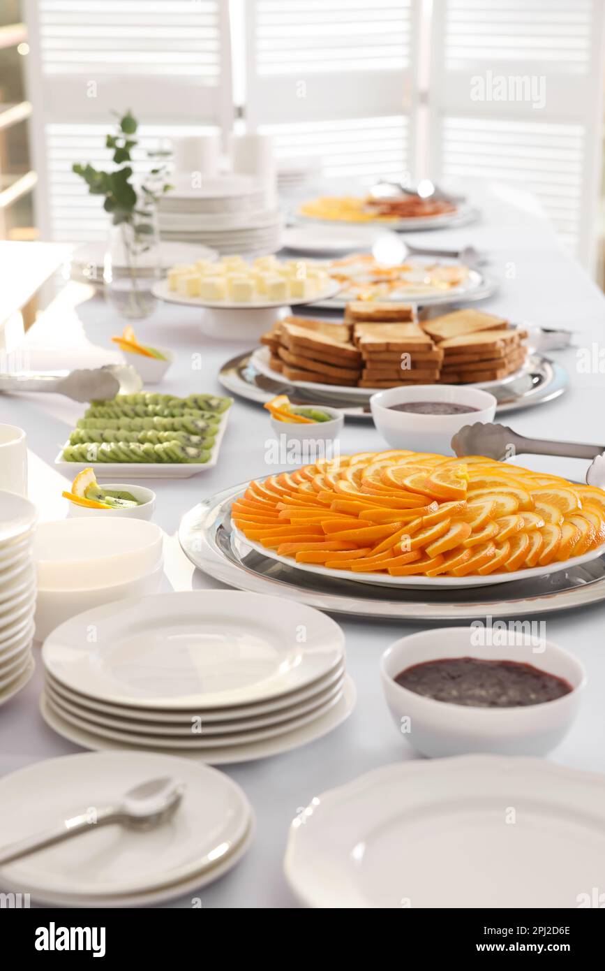 Clean dishware and different meals for breakfast on white table indoors ...