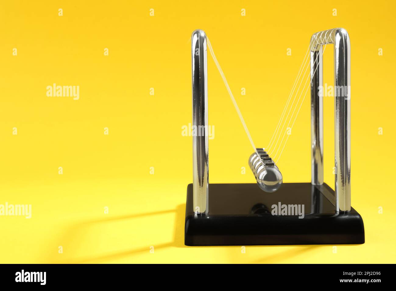 Newton's cradle on yellow background, space for text. Physics law of ...