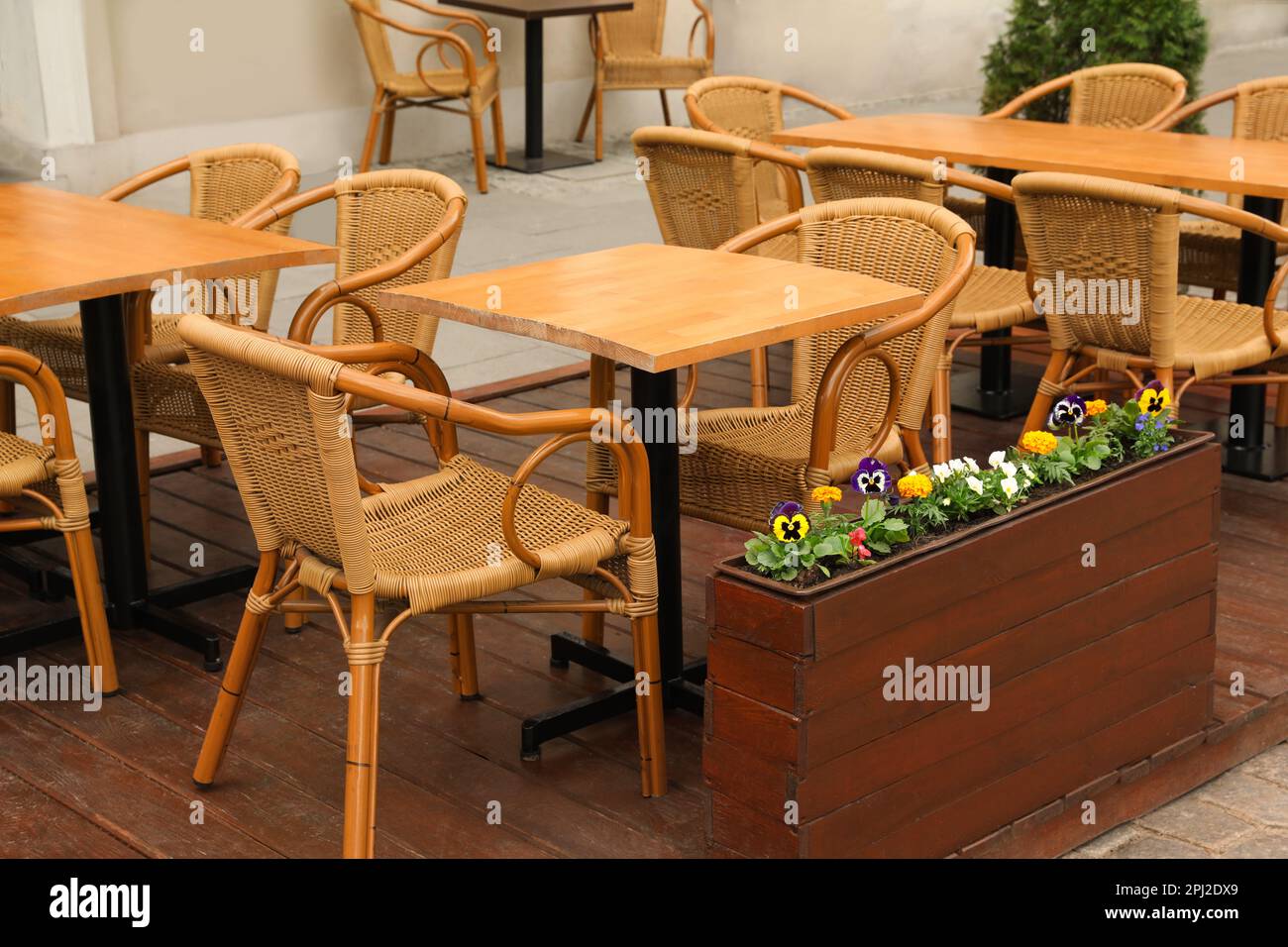 Outdoor cafe with wicker chairs and wooden tables Stock Photo - Alamy