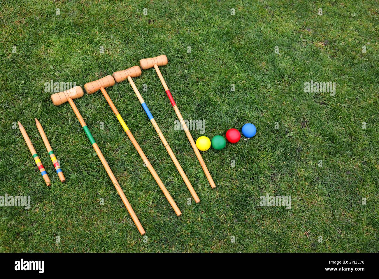 Set of croquet equipment on green grass, above view. Space for text ...