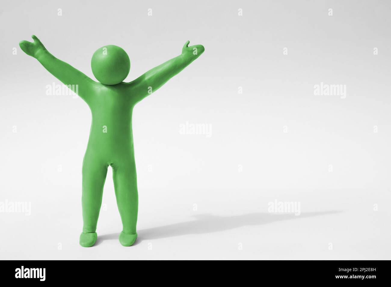 Human figure with arms wide open made of green plasticine on white ...