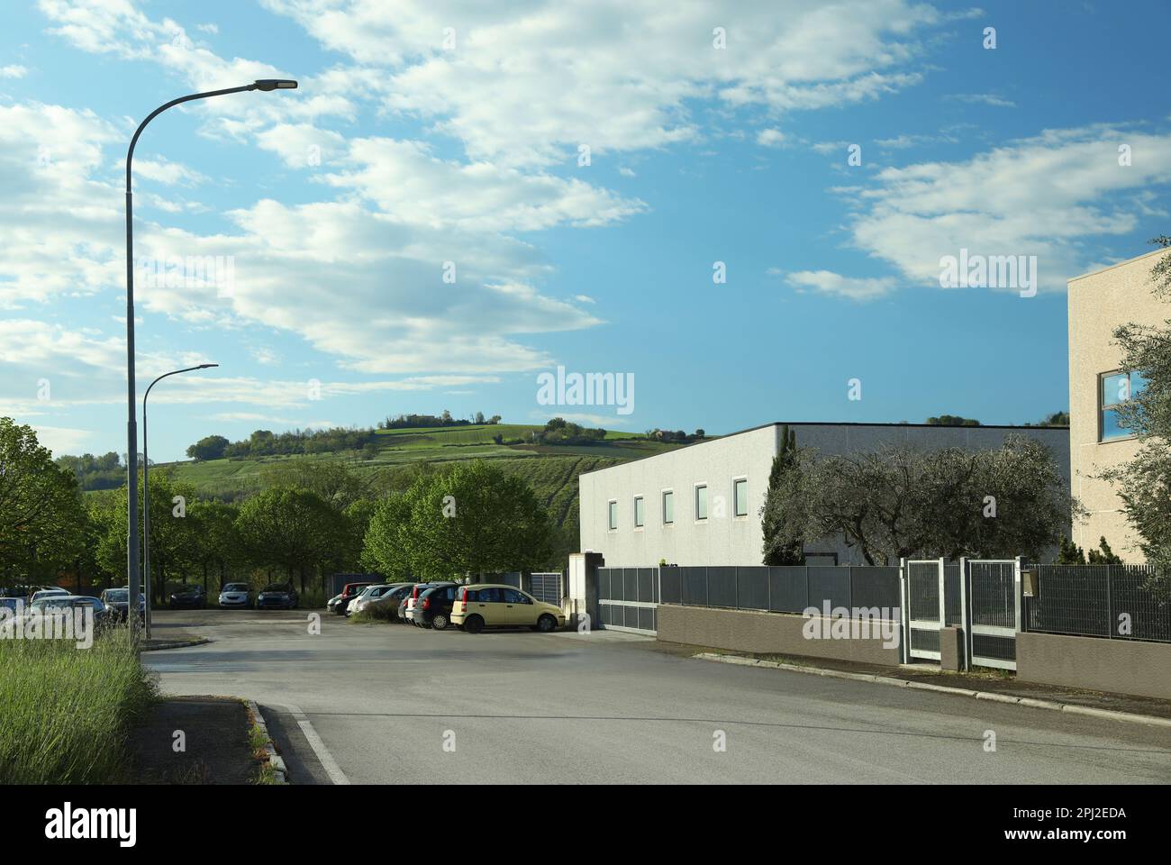 Parking lot with cars near factory building in countryside on sunny day ...