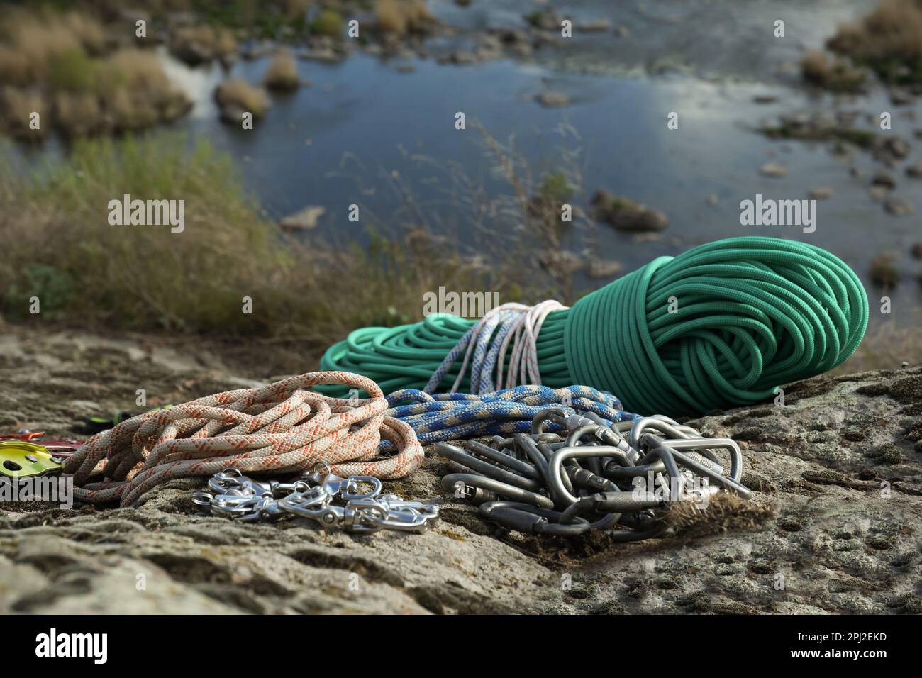 Different ropes and other climbing equipment on rock near river Stock ...