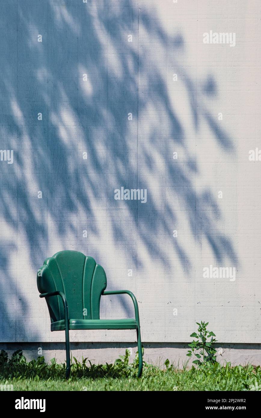 Vintage green metal scallop shell chair on lawn in front of white sun ...