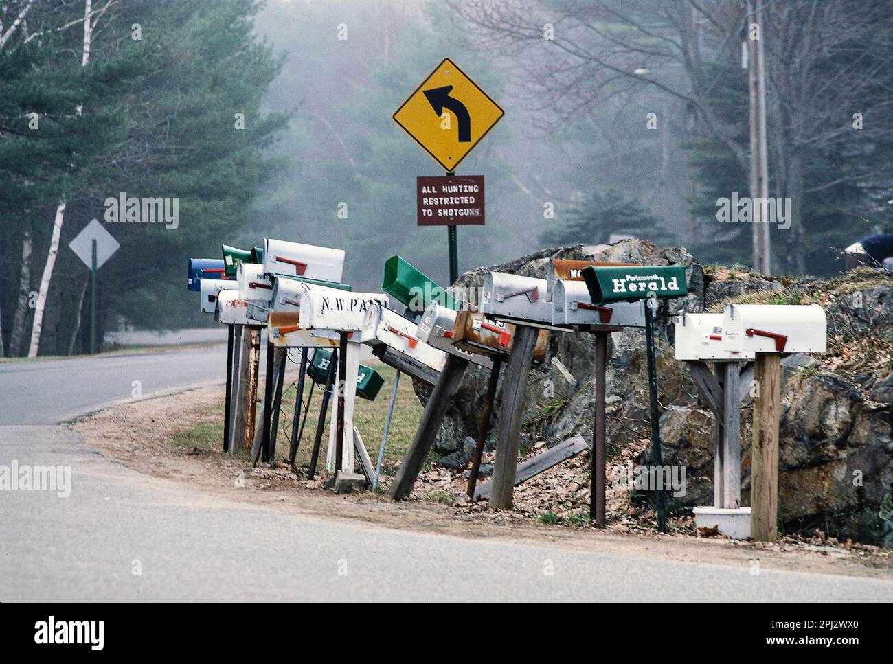 Cluster of roadside mailboxes crowd together on curvy foggy rural ...
