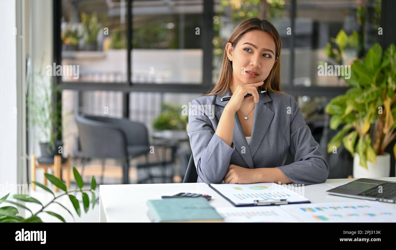 Confident and thoughtful millennial Asian businesswoman pondering and ...