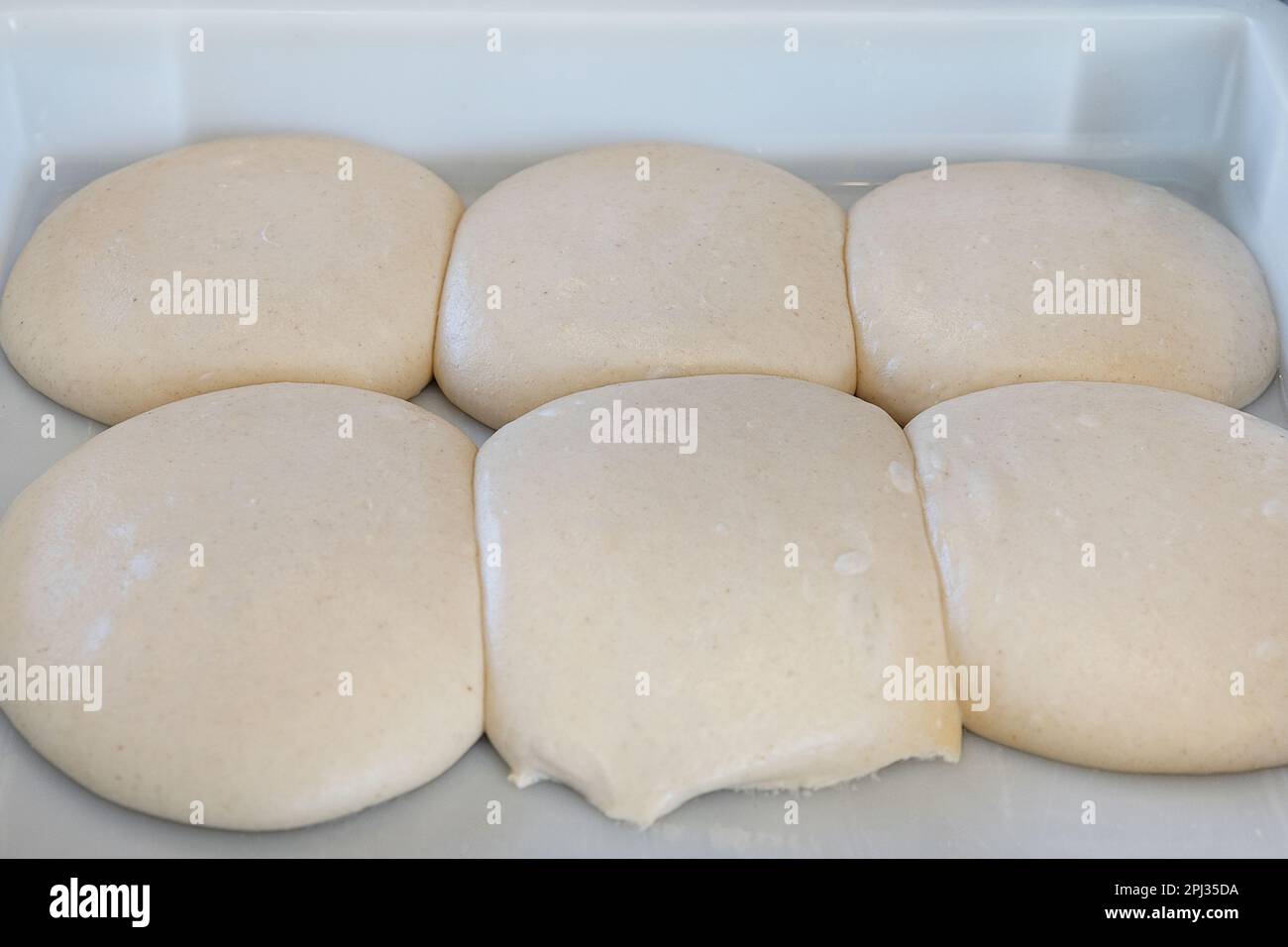 Fermenting dough divided in piles and set in a tray to rest, artisan ...