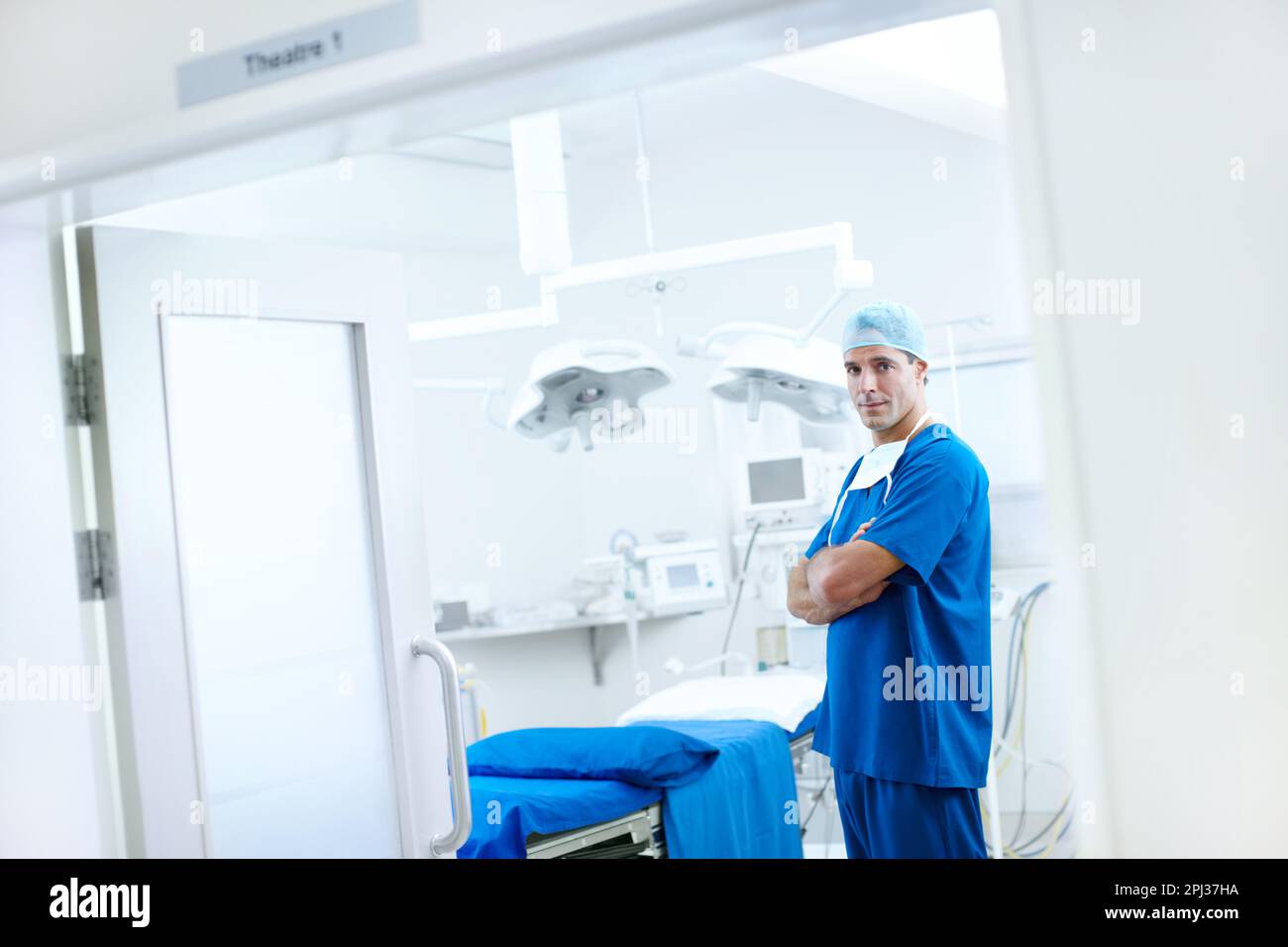I take pride in my operating theatre. A handsome male doctor standing ...