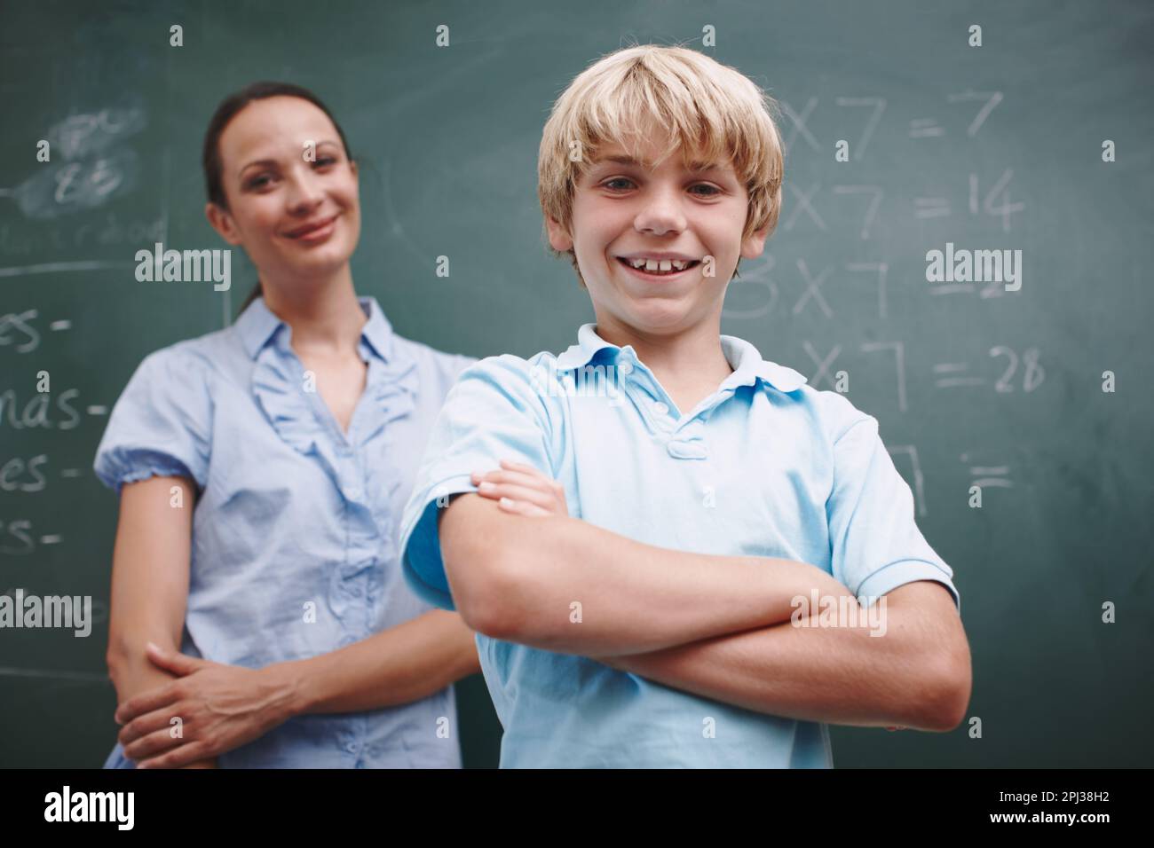 Hes her star pupil. A happy young boy crossing his arms as his teacher ...