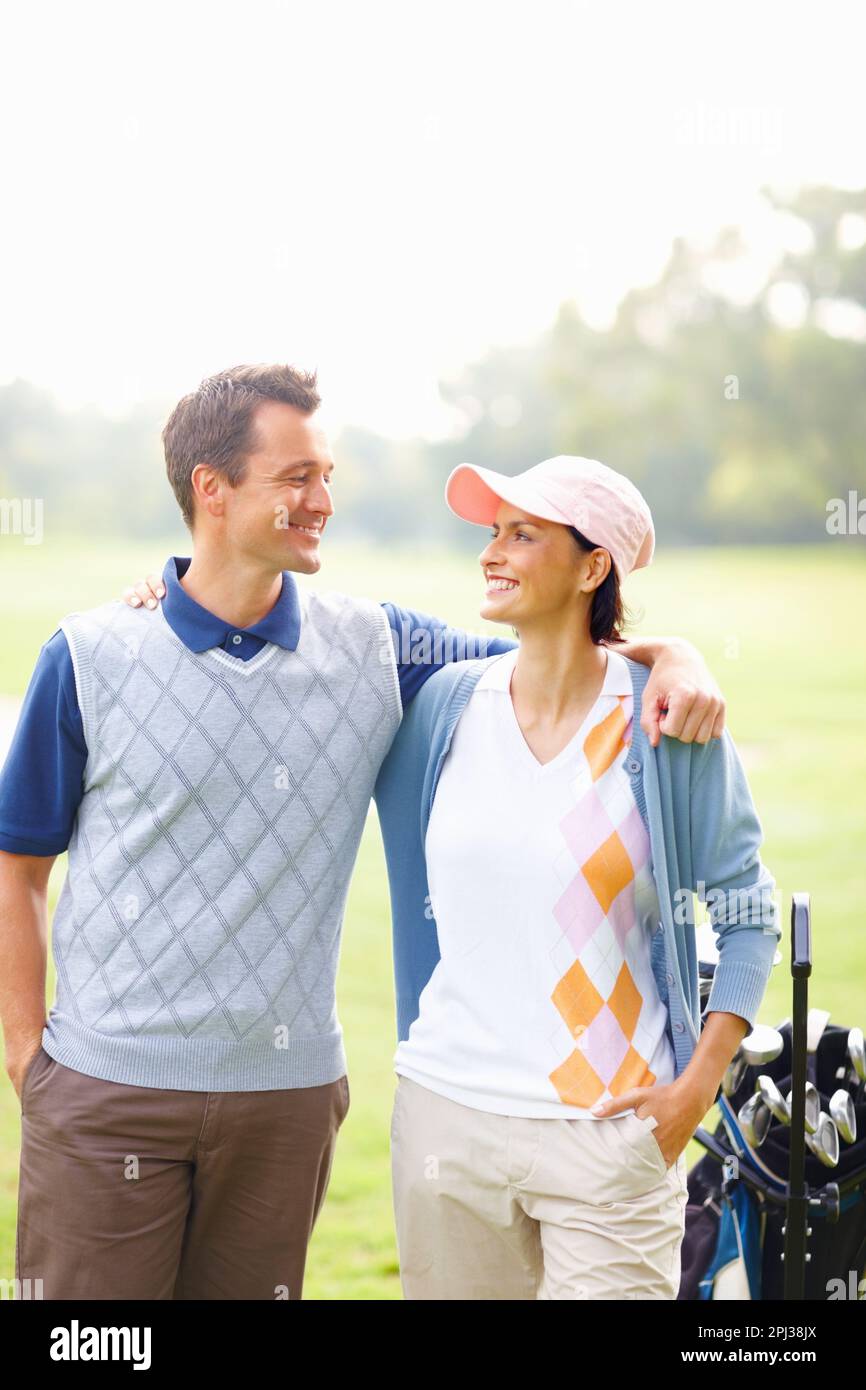 Couple ready for a game of golf. Golfing couple with arms around ...