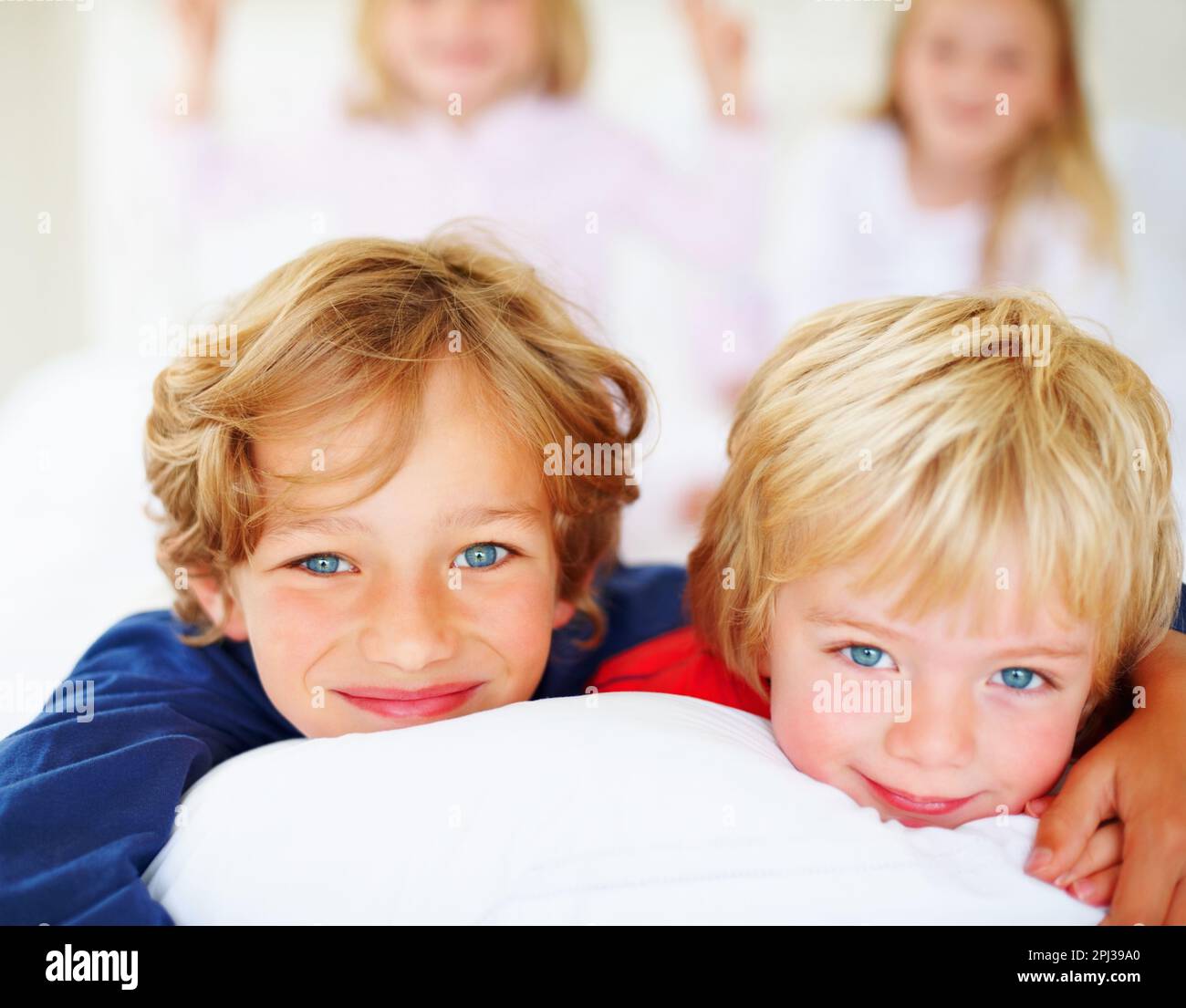 Two cute brothers with their blur sisters at back. Closeup portrait of ...