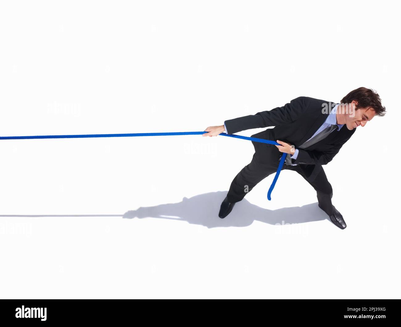 A young business man pulling a rope on white. A young business man ...