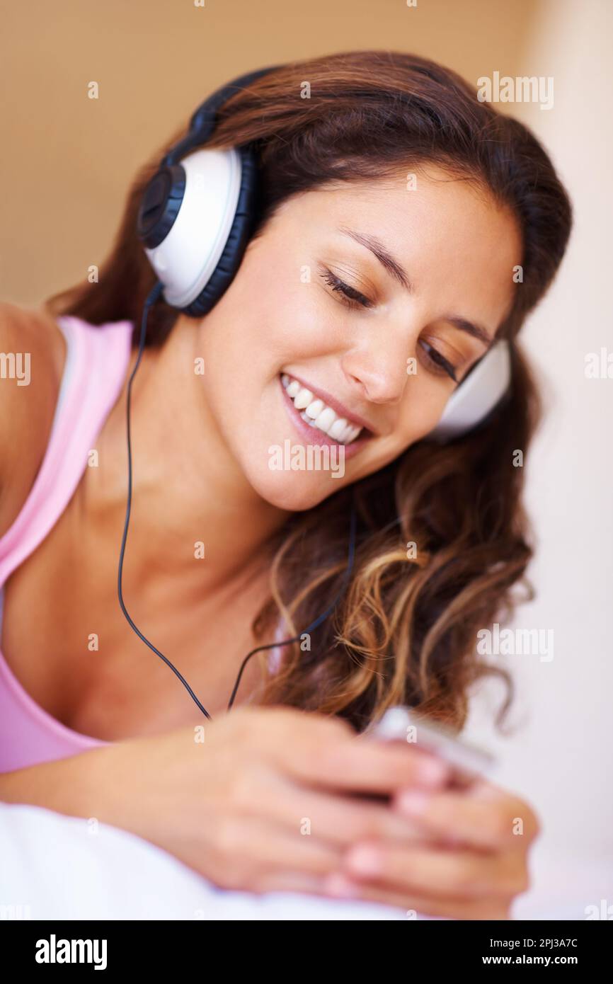 Listening to music. Smiling female listening to music on her mp3 player ...