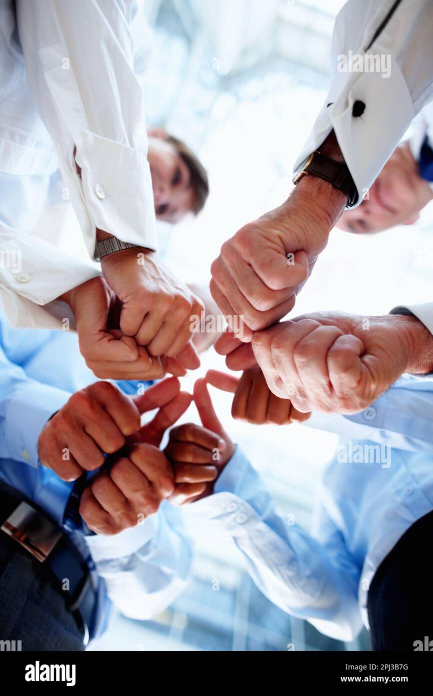 Teamwork equals success. Low angle view executives holding their thumbs ...