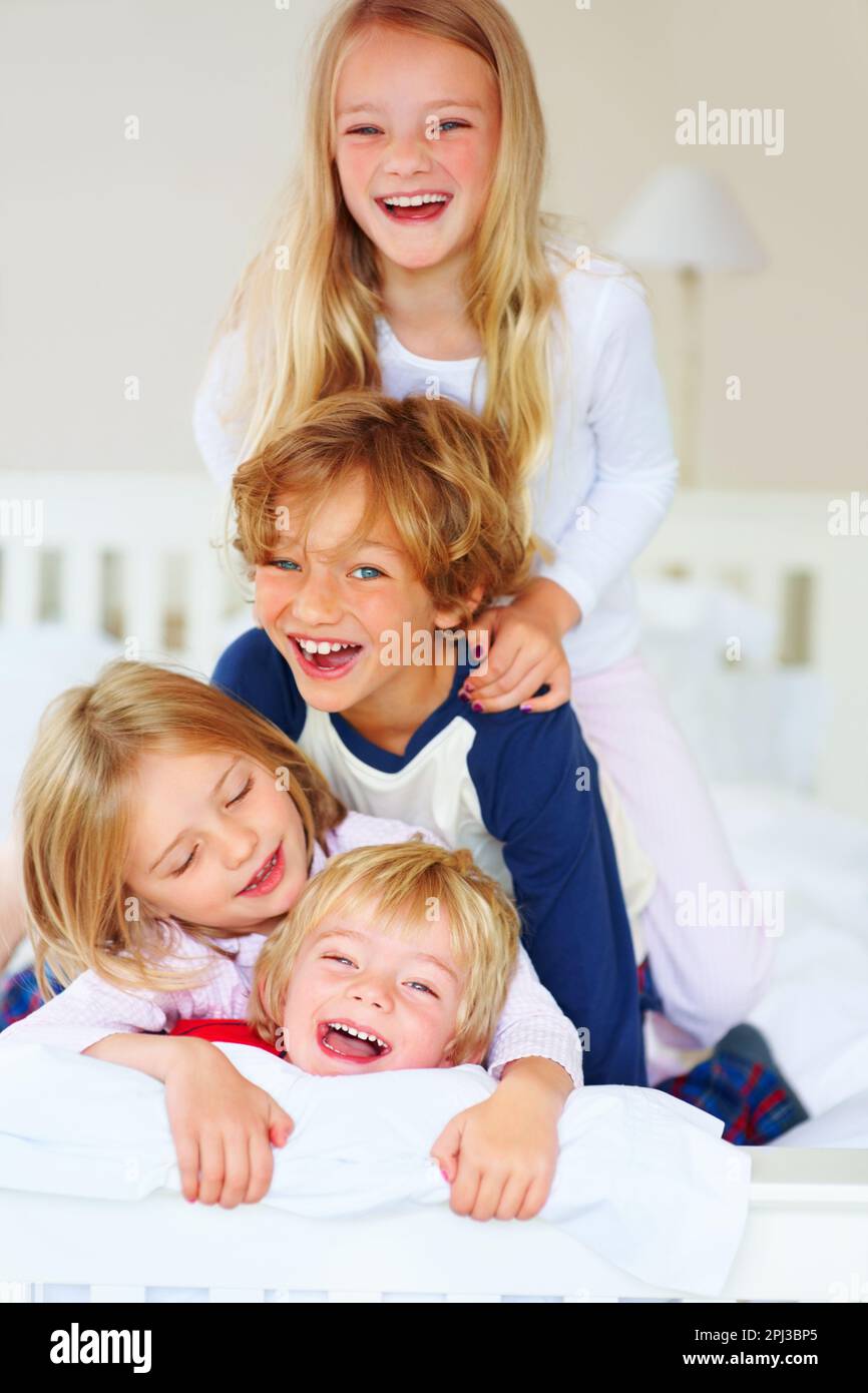Joyful little brothers and sisters playing together in bed. Portrait of ...