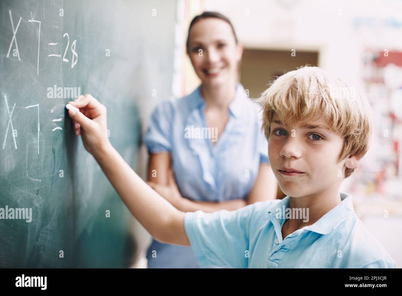 Extra lessons. A young boy doing mathematics on the blackboard as his ...