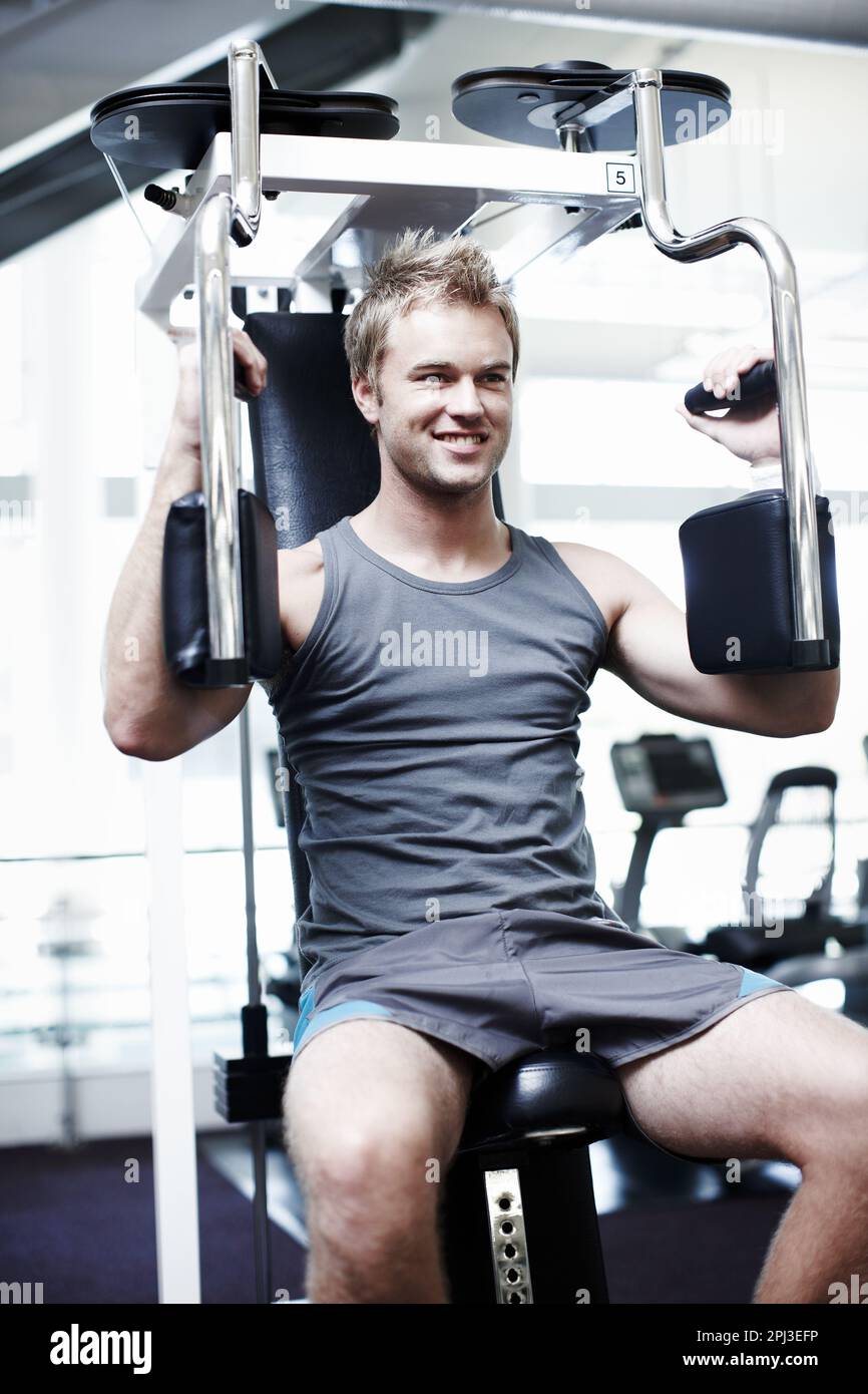 Dedicated to fitness. a handsome young man using an exercise machine in ...