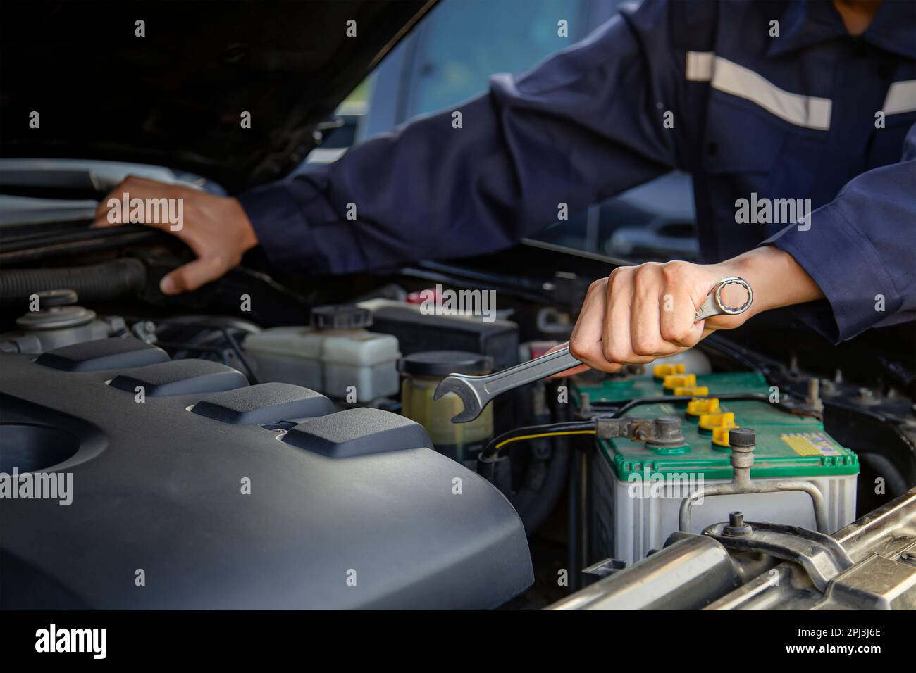 The mechanic works on the engine of the car in the garage, car repair ...