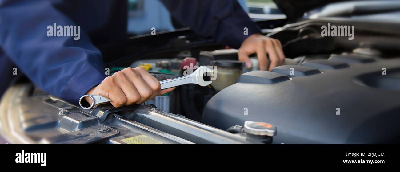 The mechanic works on the engine of the car in the garage, car repair ...