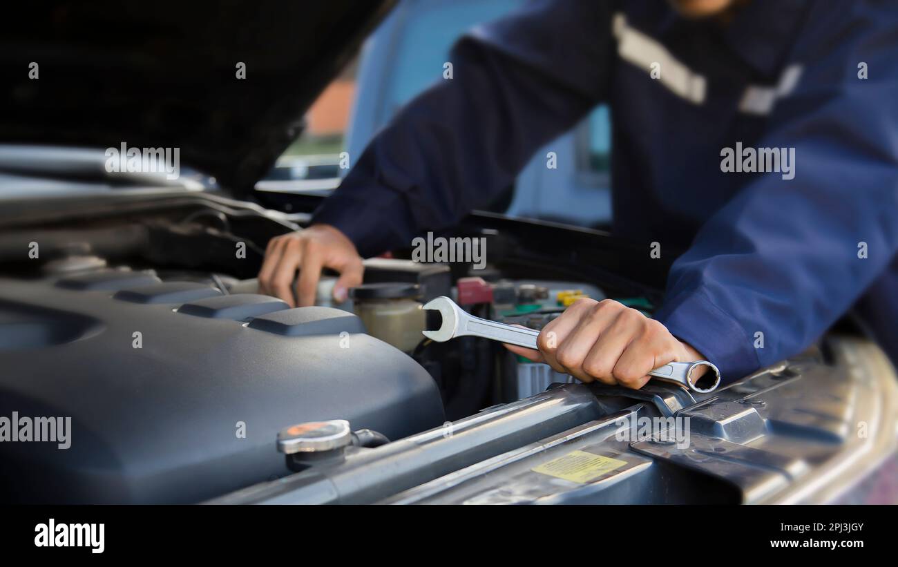 The mechanic works on the engine of the car in the garage, car repair ...