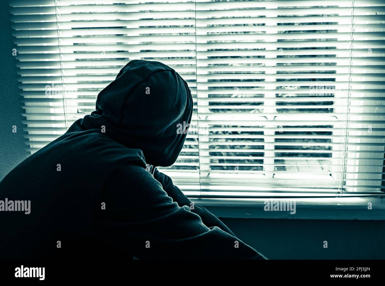 Toned Photo of Sad Young Man in a Hoodie by the Window in the Room ...