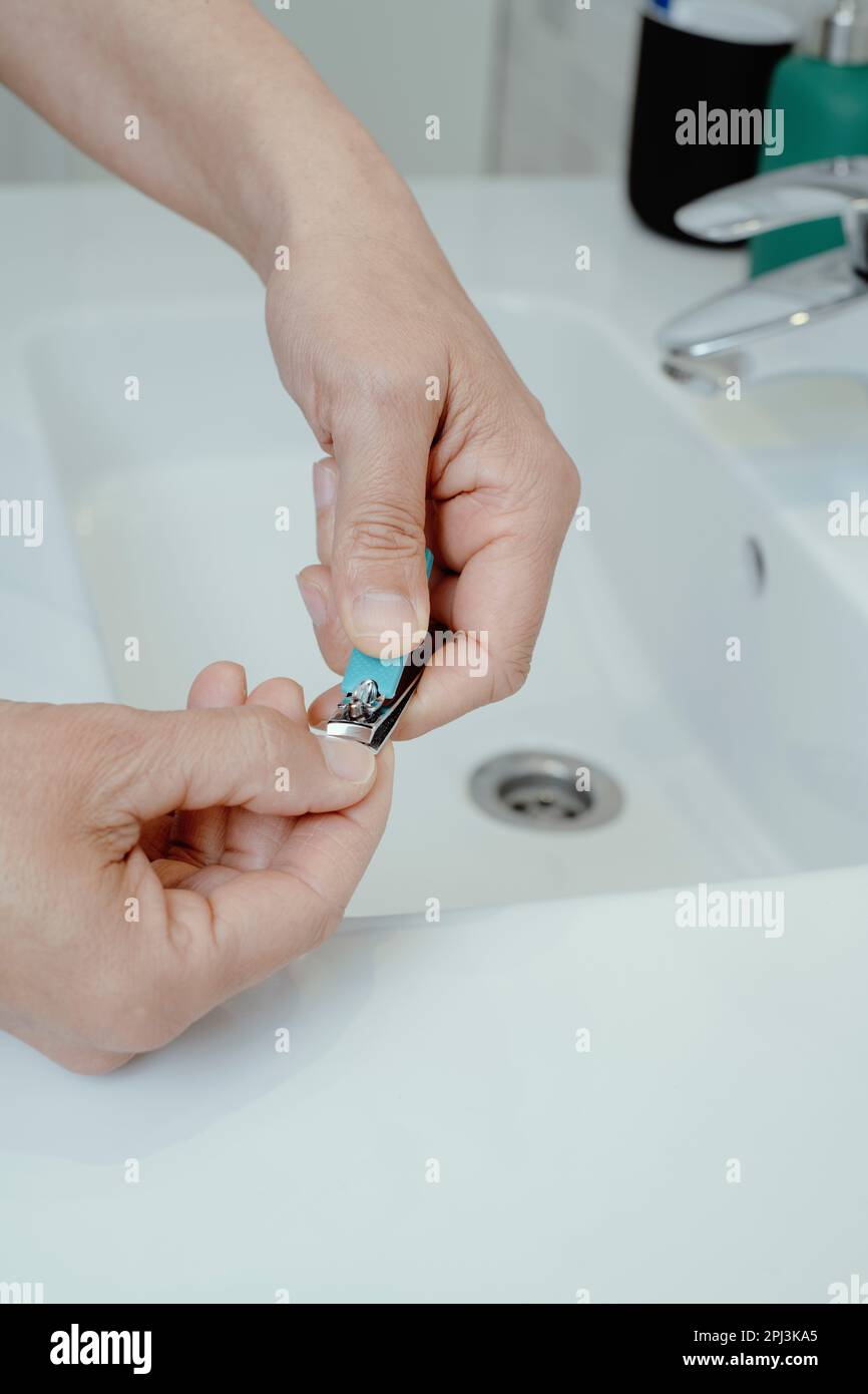 closeup of a man cutting his fingernails with a nail clipper, leaning ...