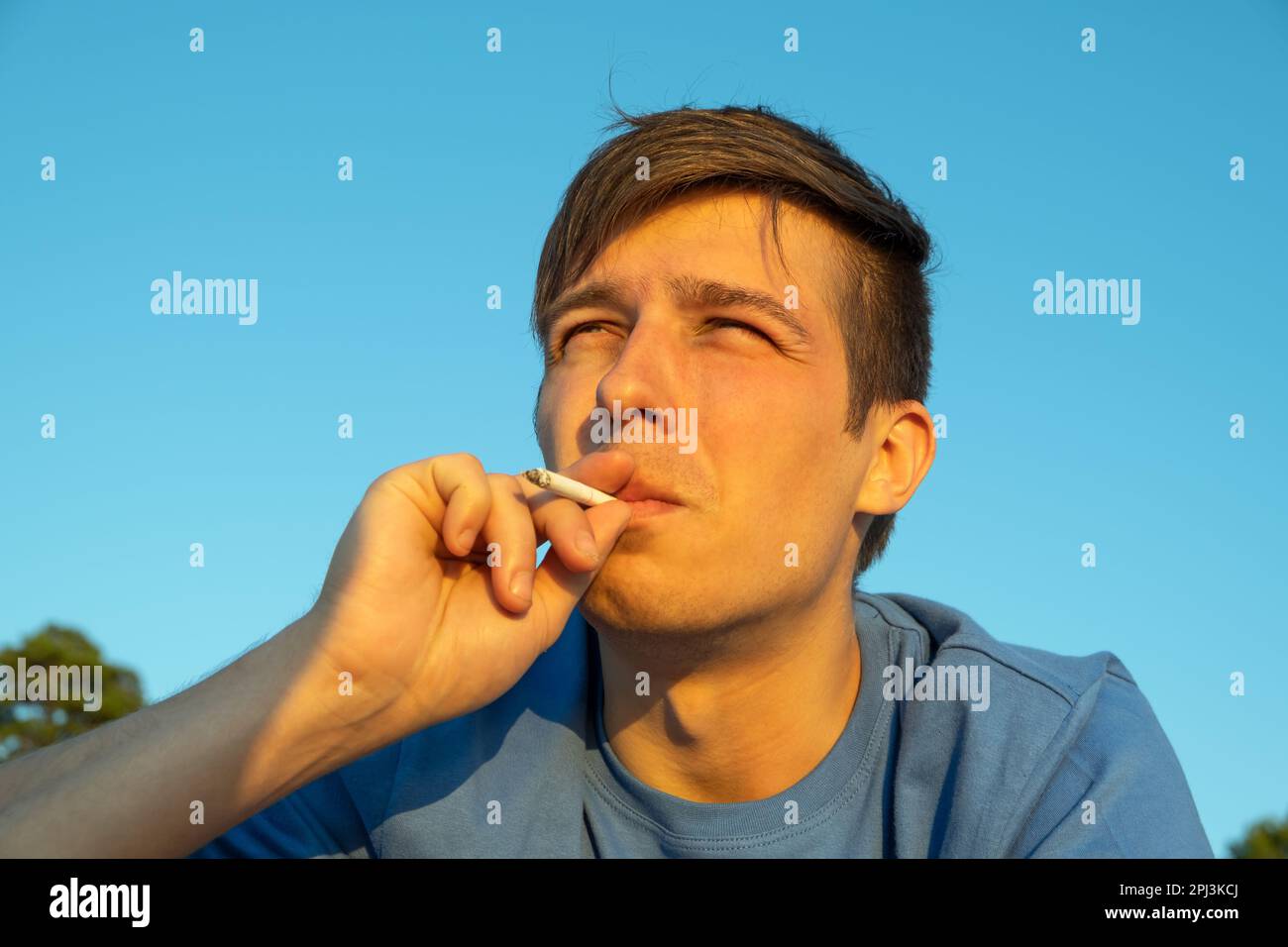 Young Man smoking a Cigarette on the Sky Background Stock Photo - Alamy