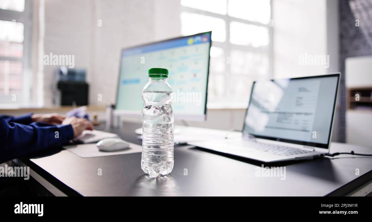 Water Bottle On Desk And Man In Background Using Computer Stock Photo ...