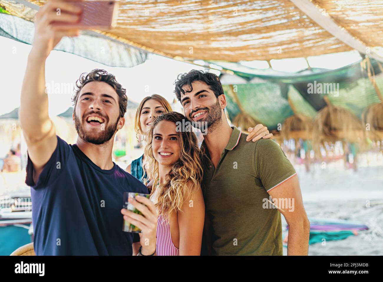 Four young friends, two men and two women, hugging and taking a selfie ...