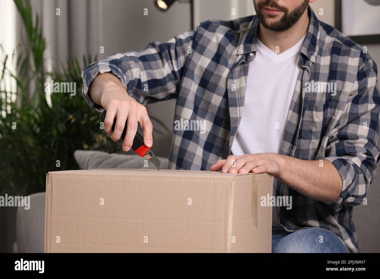 Man using utility knife to open parcel at home, closeup Stock Photo - Alamy