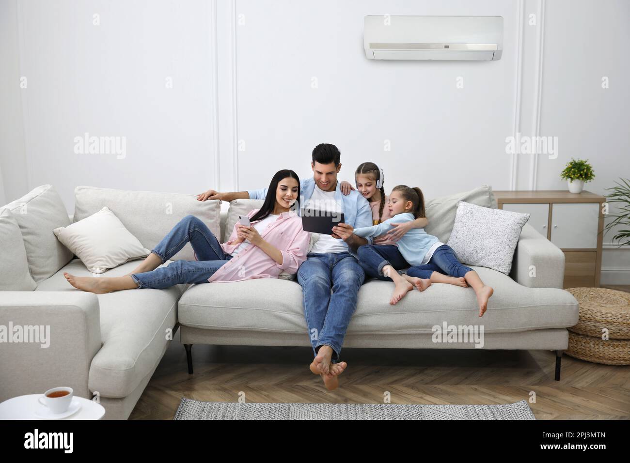 Happy family resting under air conditioner on white wall at home Stock Photo - Alamy
