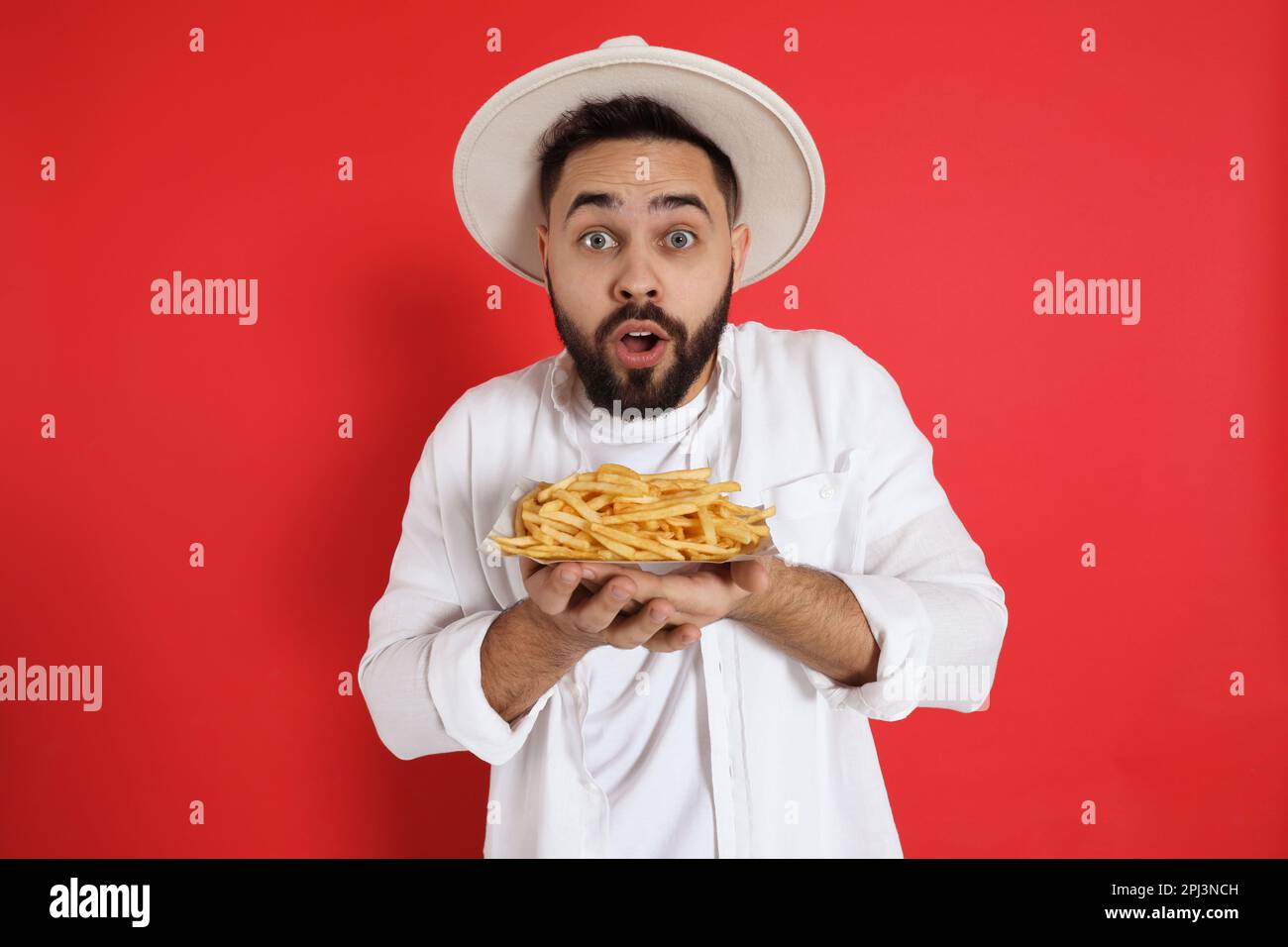 Emotional young man with French fries on red background Stock Photo - Alamy