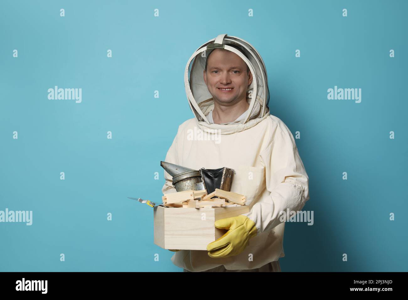 Beekeeper in uniform with tools on light blue background Stock Photo ...