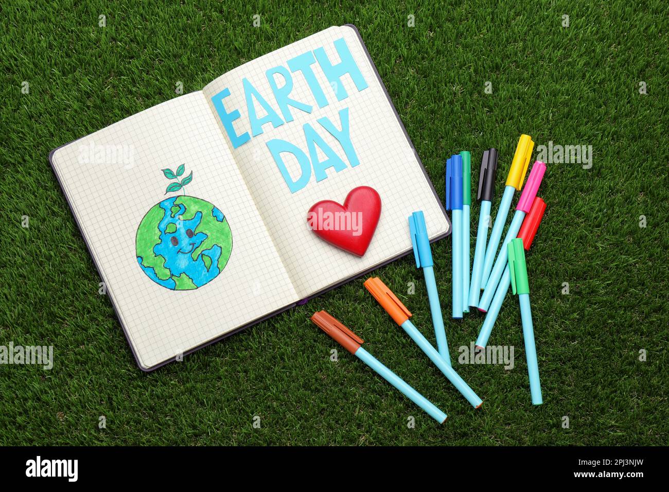 Notebook with words Earth Day, planet drawing and markers on green ...