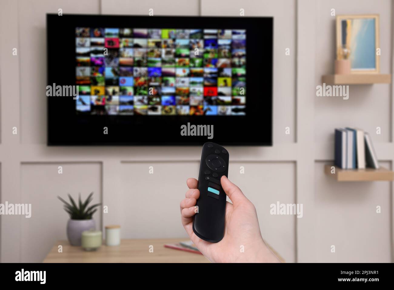 Woman with remote control changing channels while watching TV at home ...
