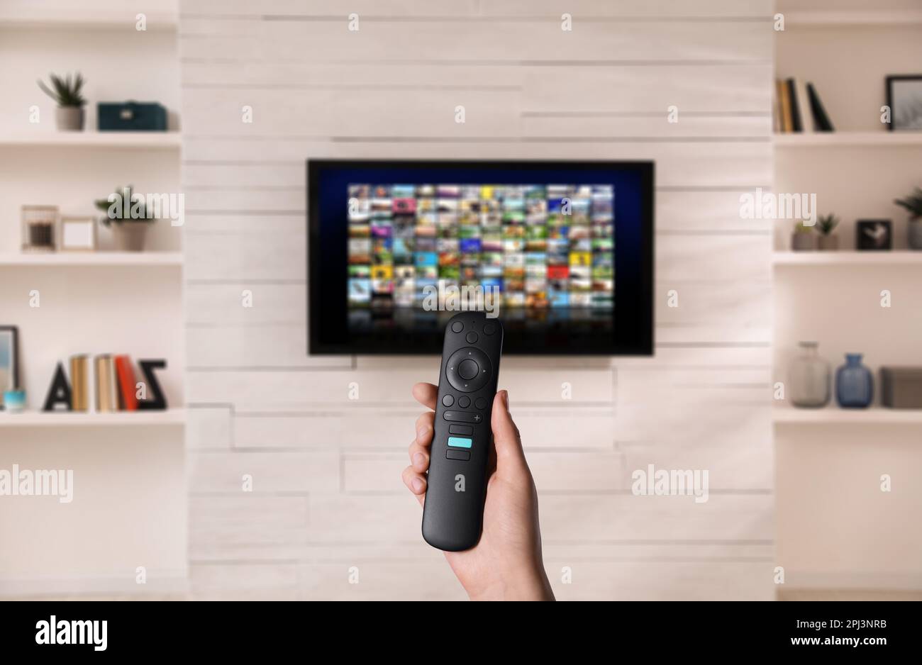 Woman with remote control changing channels while watching TV at home ...