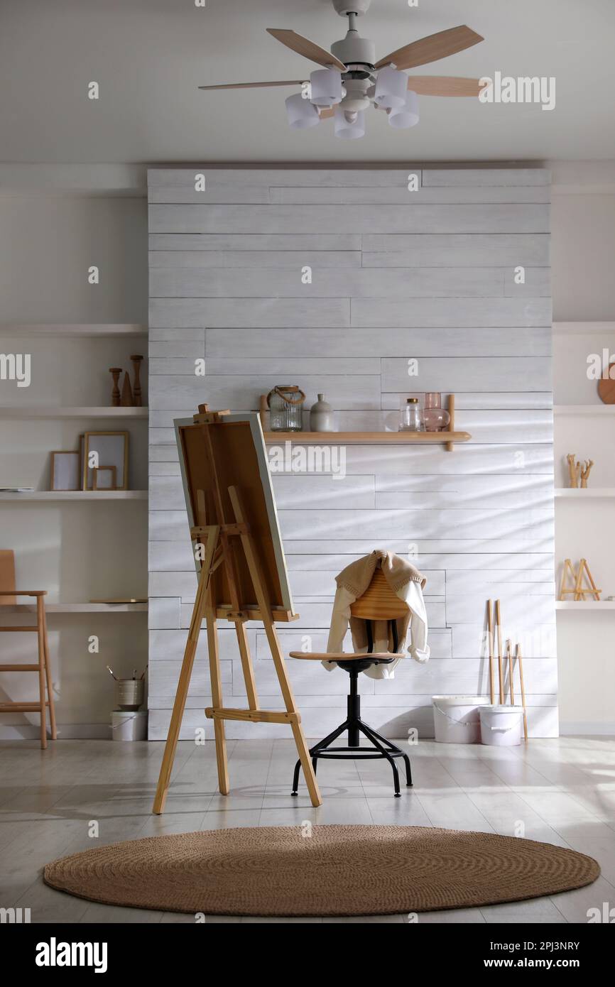 Modern studio interior with wooden easel and chair. Artist's workplace ...