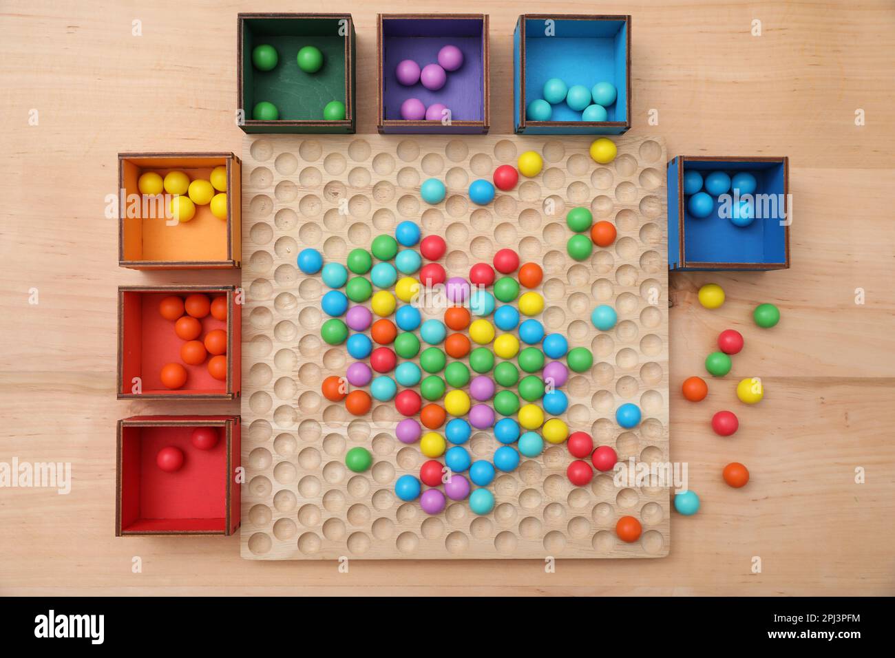 Wooden sorting board and boxes with colorful balls on table, flat lay ...