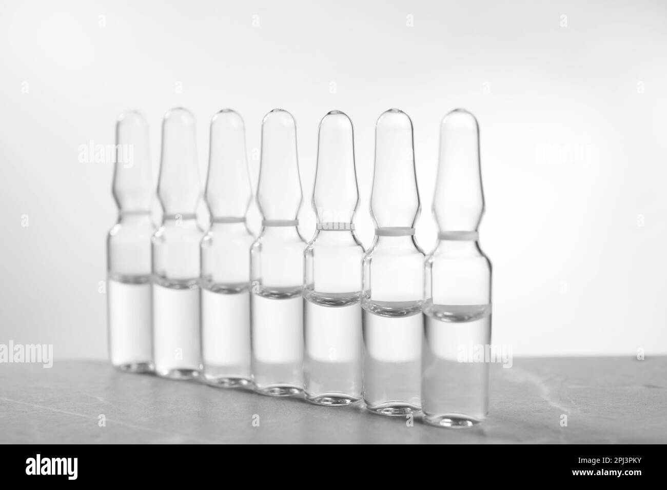 Pharmaceutical ampoules with medication on grey table against light ...