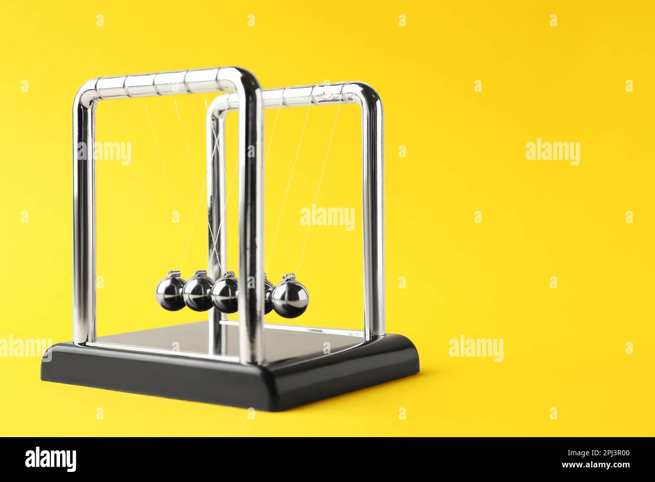 Newton's cradle on yellow background, space for text. Physics law of ...