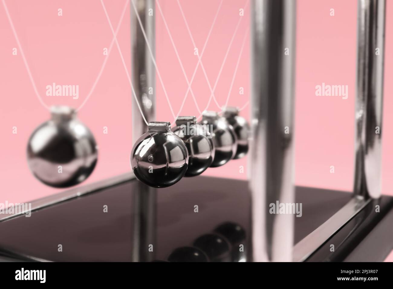 Newton's cradle on pink background, closeup. Physics law of energy ...