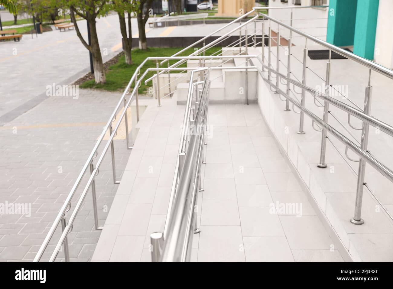 Tiled ramp with shiny metal railings outdoors Stock Photo - Alamy