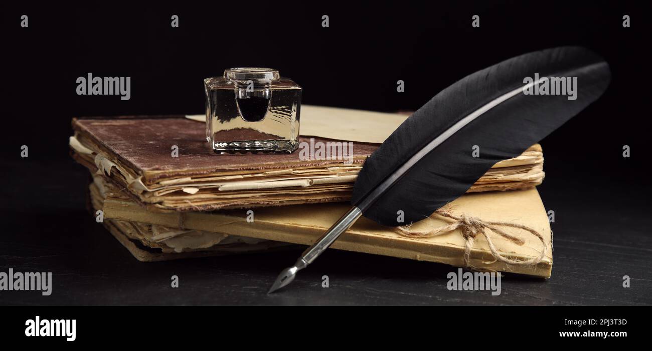 Quill, inkwell and old books on black table. Banner design Stock Photo ...
