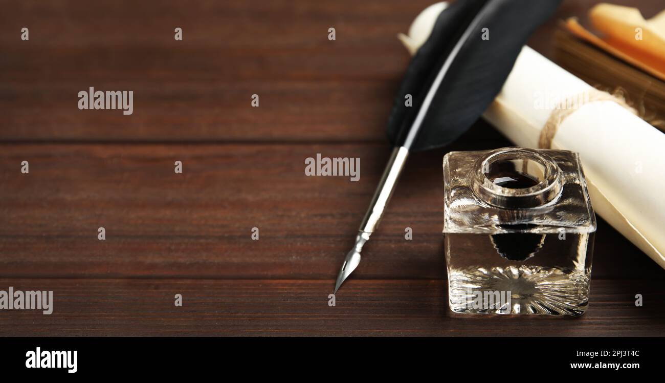 Quill, inkwell and paper roll on wooden table, space for text. Banner ...