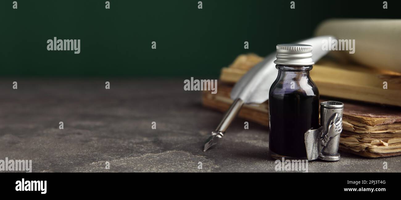 Composition with quill and bottle of ink on grey table, space for text ...