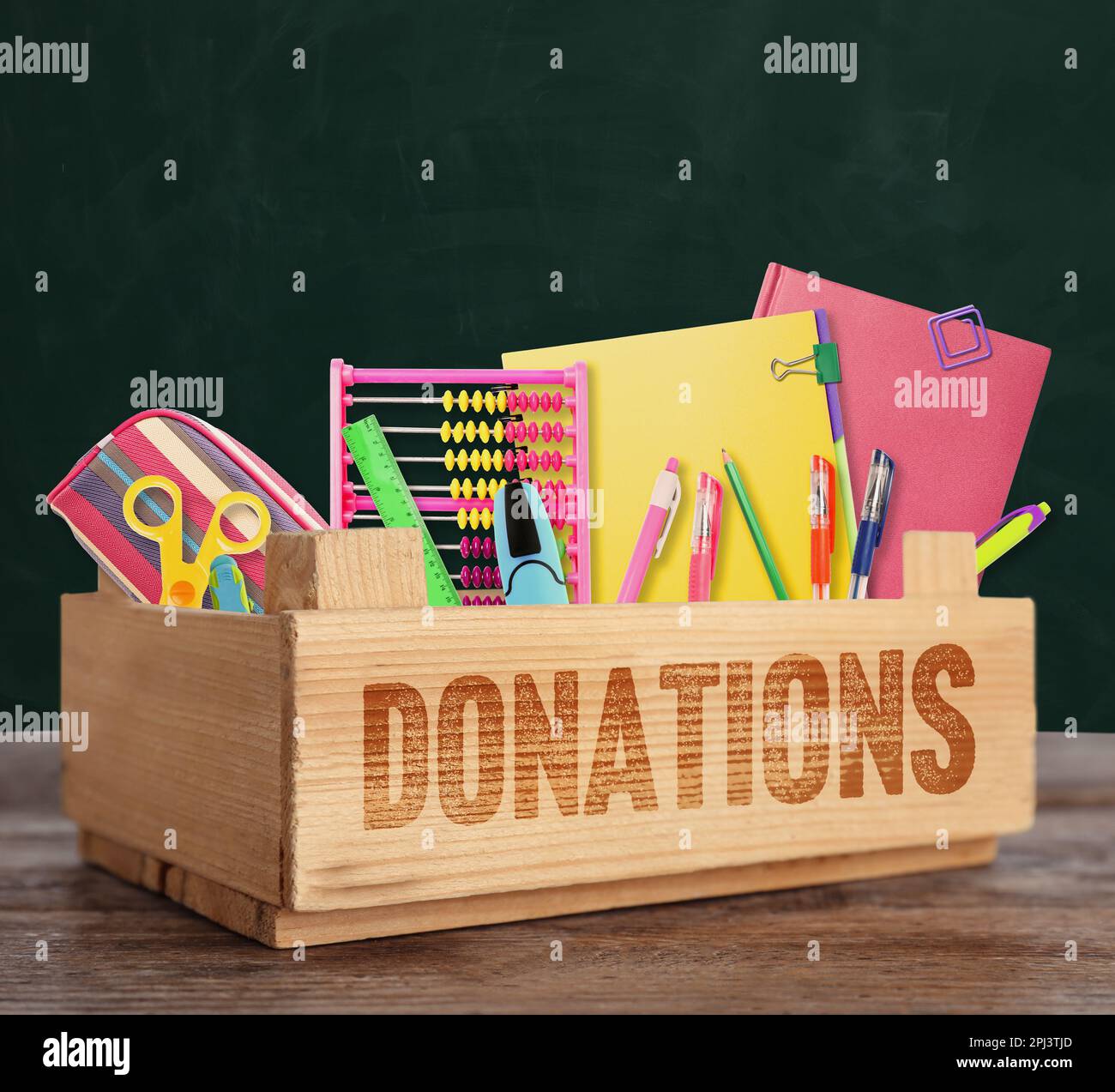 Donation box with different school stationery on wooden table near ...