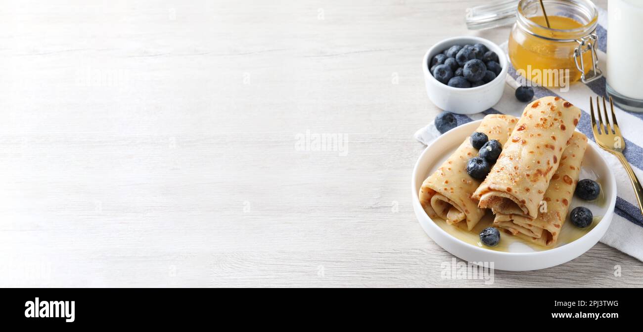 Delicious crepes served with blueberries, honey and milk on white ...